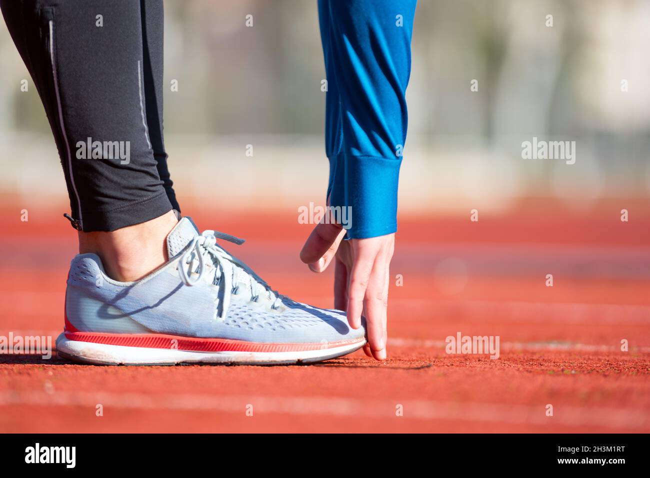 Close up view, athlete stretching on a running track Stock Photo - Alamy