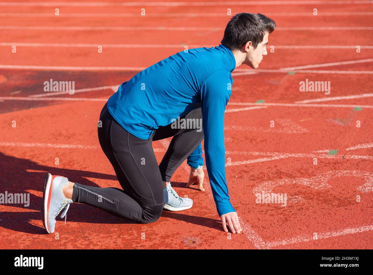 Man athlete on the starting line of a running track at the stadium ...
