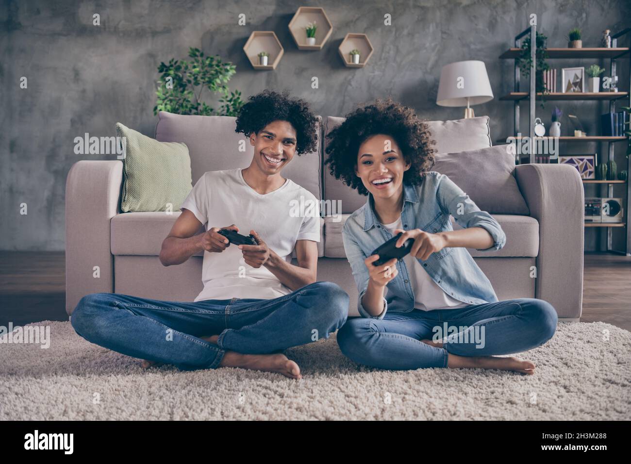 Full length body size photo young couple sitting on floor playing video ...