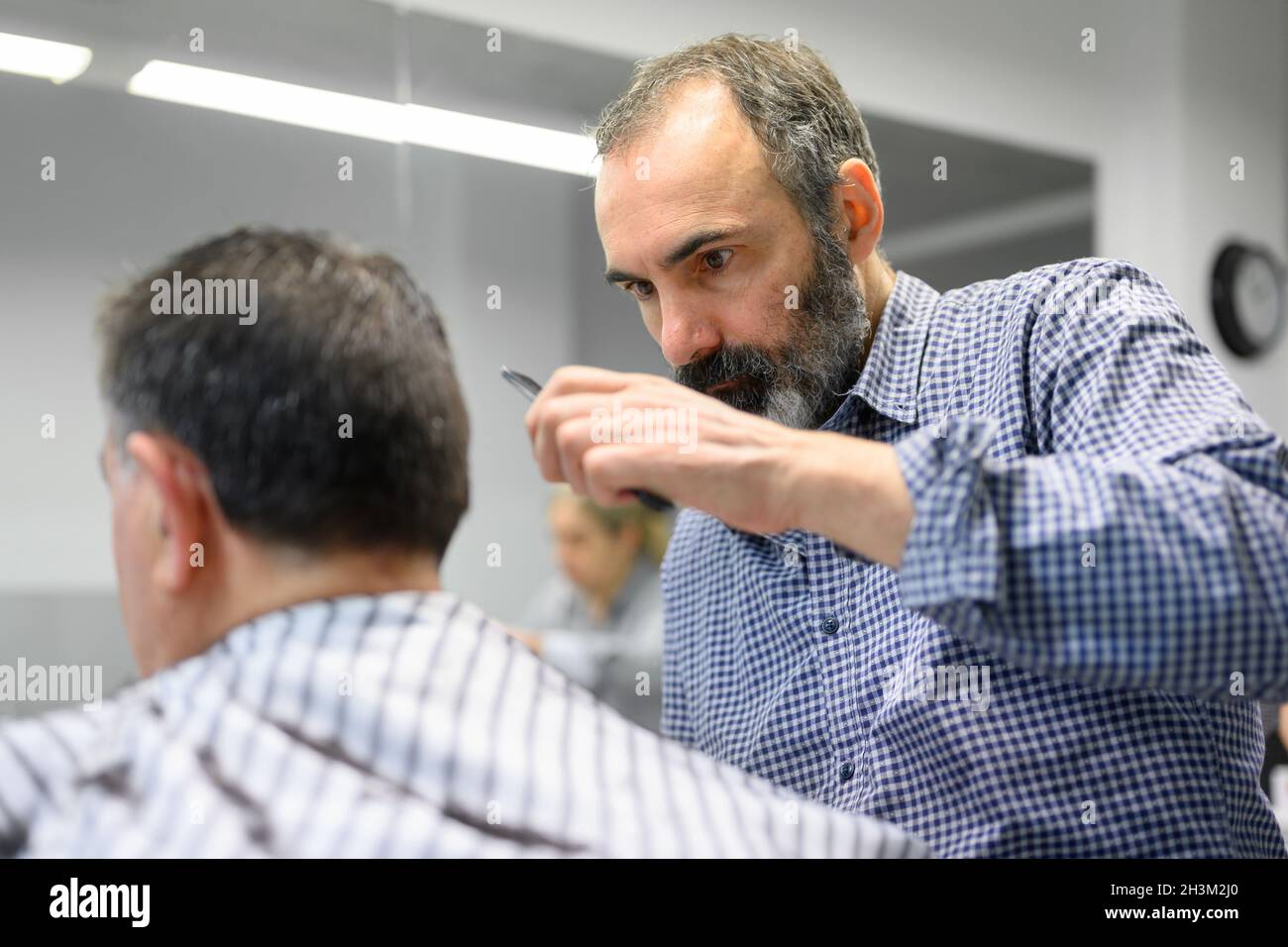 Barber trimming hair of old man at barber shop Stock Photo - Alamy