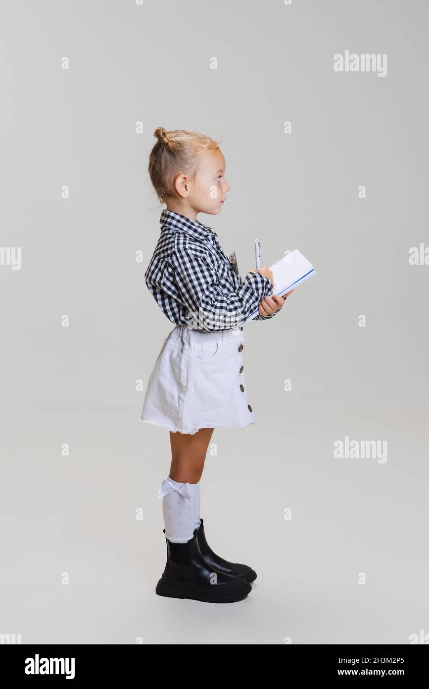 Full-length side view portrait of little cute girl, child in checkered ...