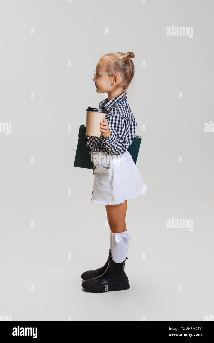 Full-length side view portrait of little cute girl, child with notebook ...