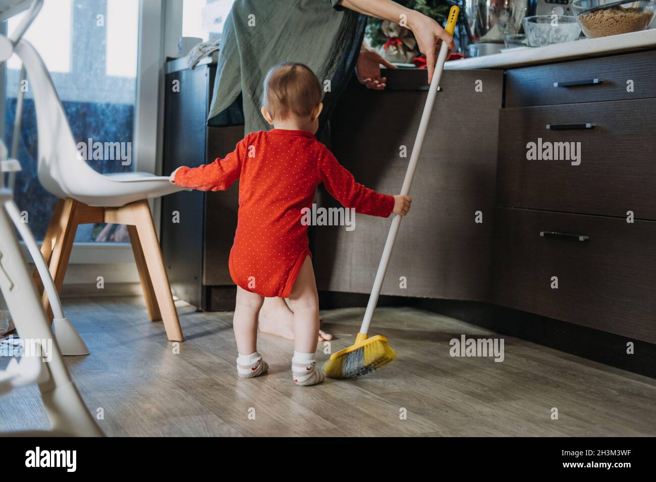 Little mothers helper. Cute toddler baby girl with mop help her mom do ...
