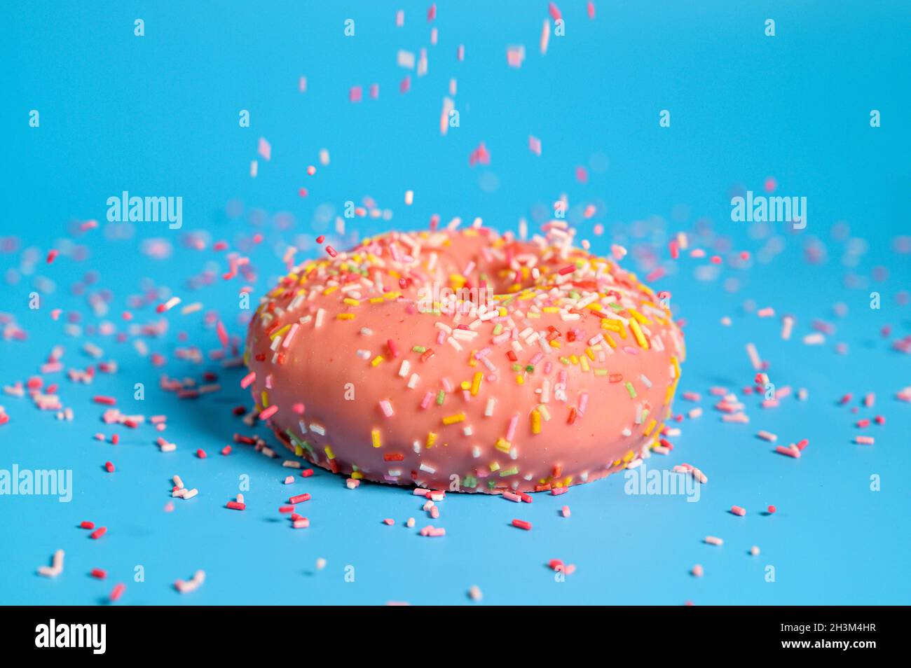 Sprinkles falling from top on Tasty pink strawberry donut. Delicious ...