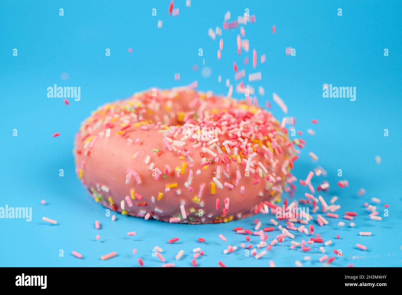Sprinkles falling from top on Tasty pink strawberry donut. Delicious ...