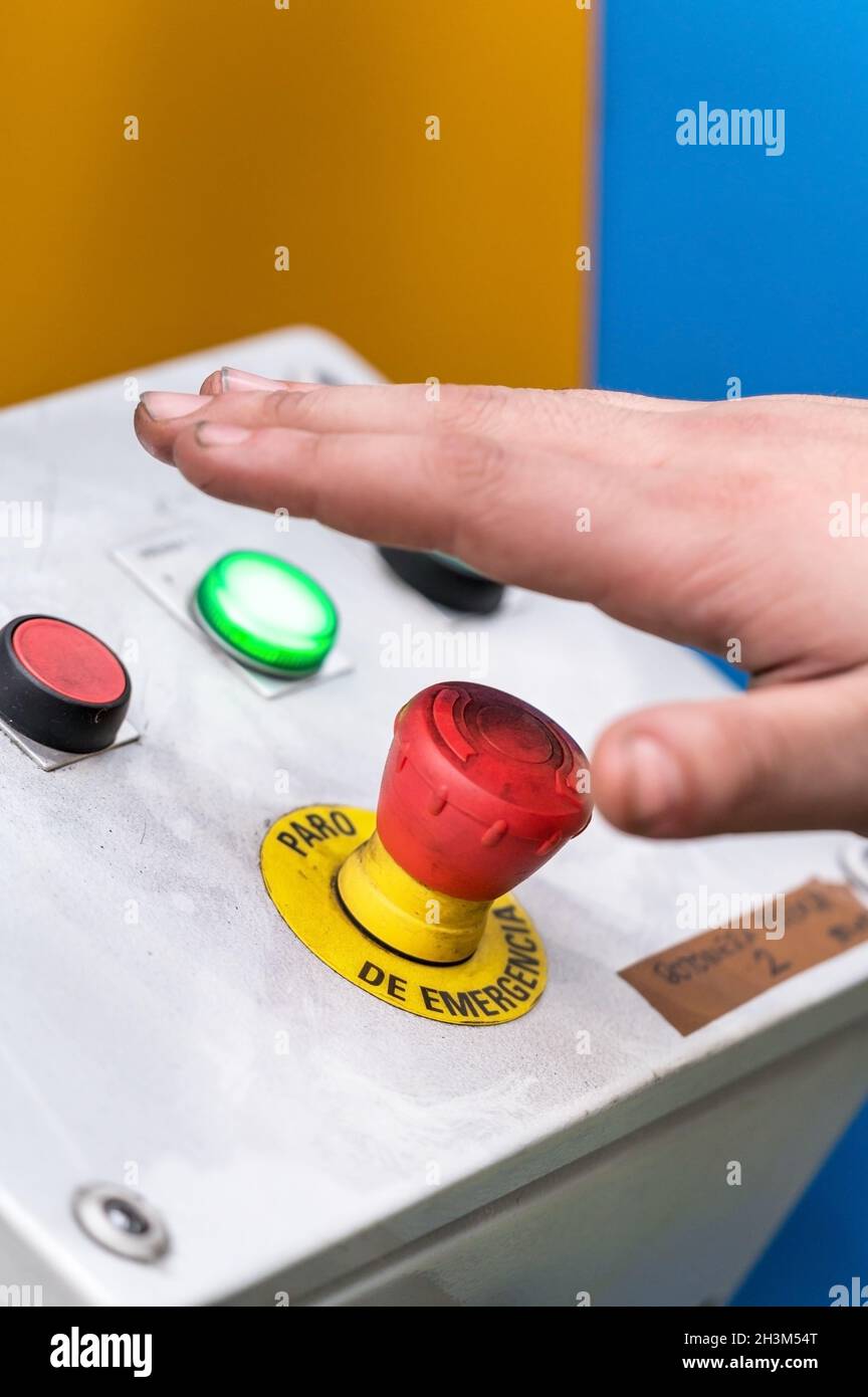 Hand pressing the red emergency button or stop button for industrial ...