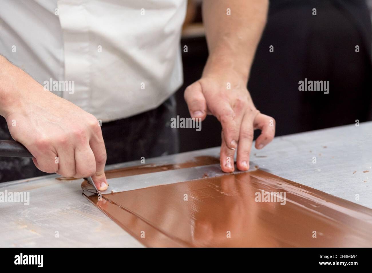 Professional confectioner making chocolate sweets at confectionery shop ...