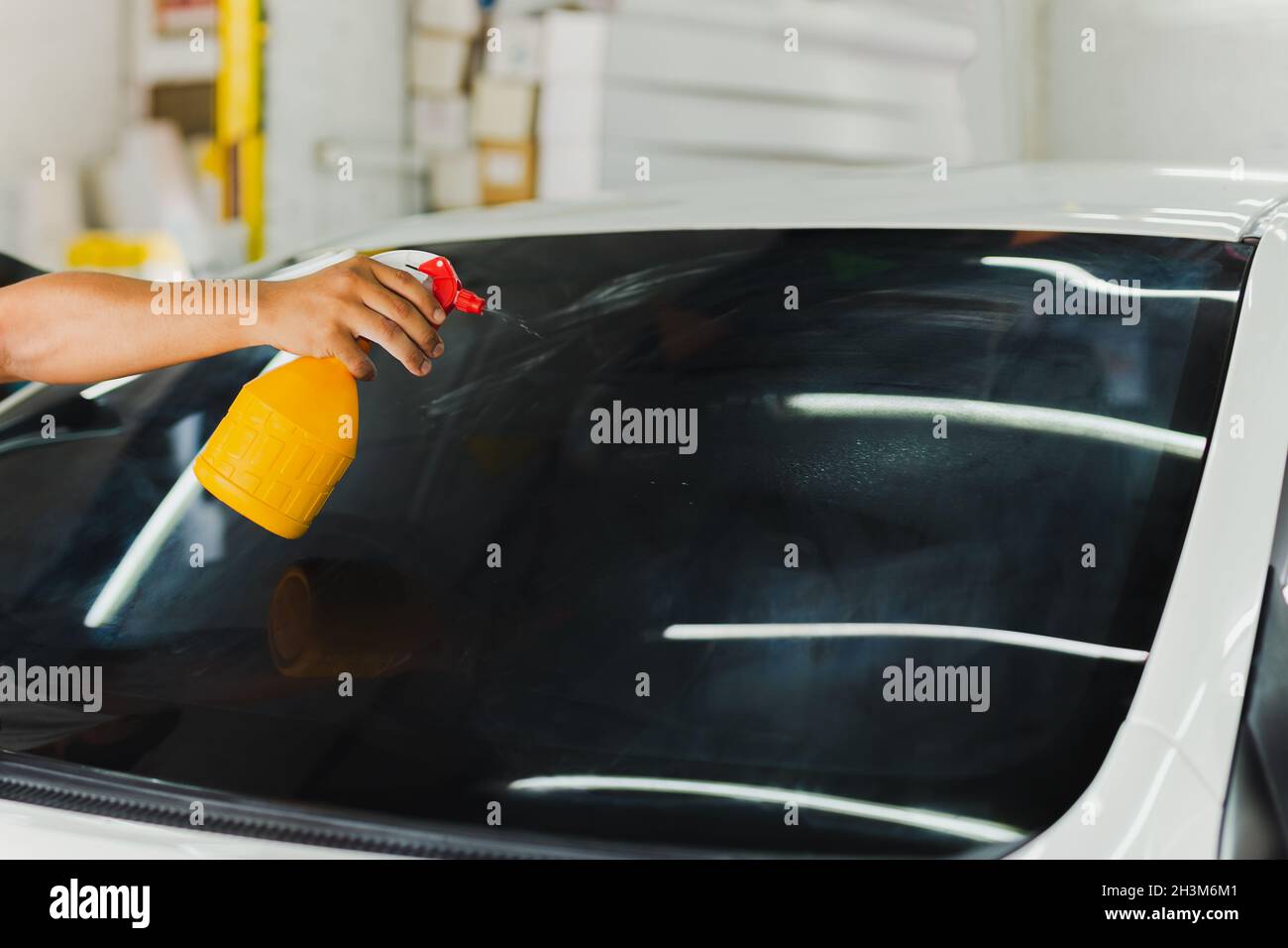 Car specialist spraying water into tinted car window in workshop Stock ...
