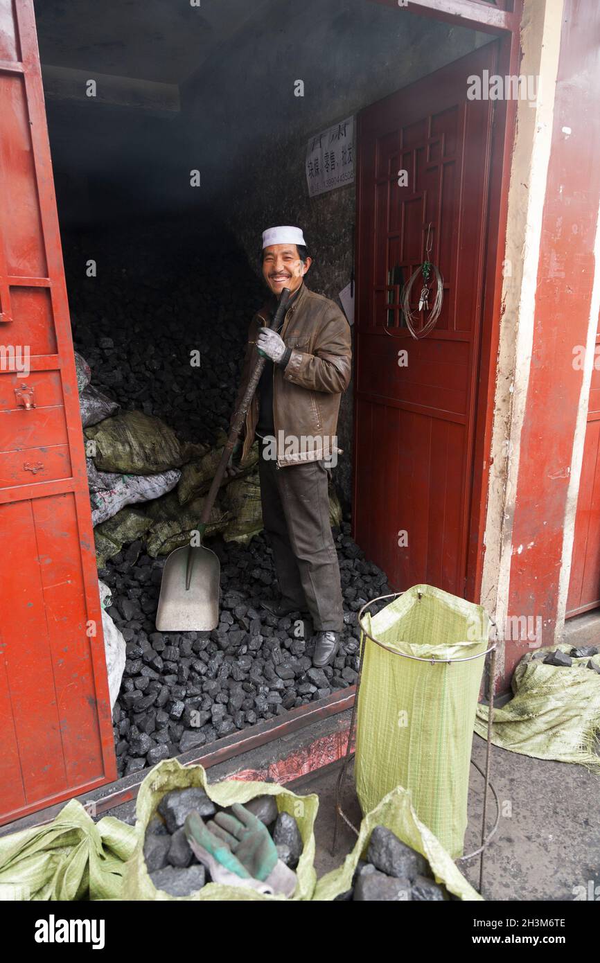 Male Muslim man with shovel bagging coal into sacks for sale or use ...