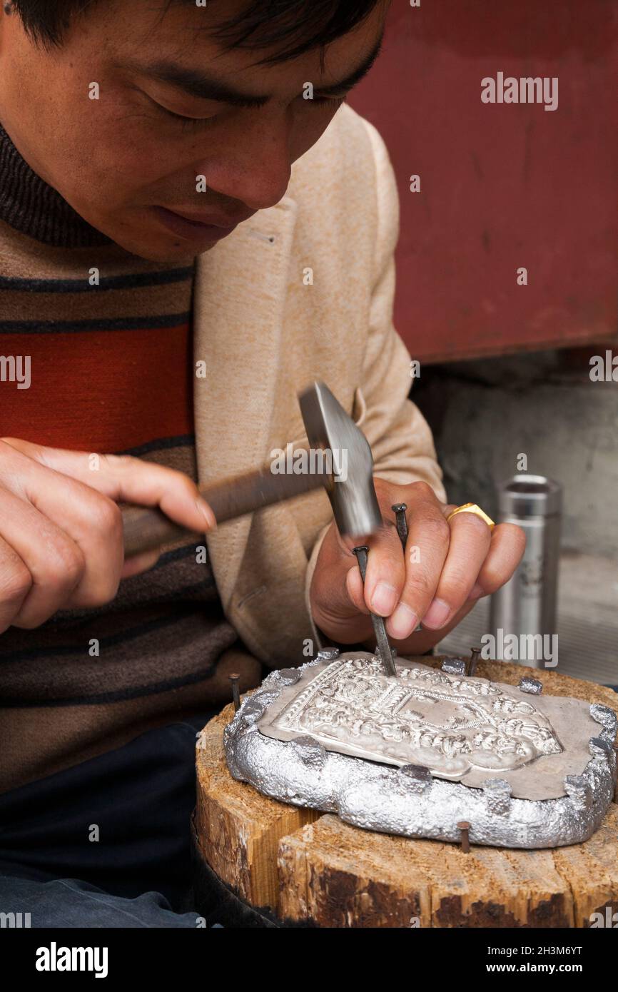 Metal worker / metalworker working with hammer on embossed metal piece ...
