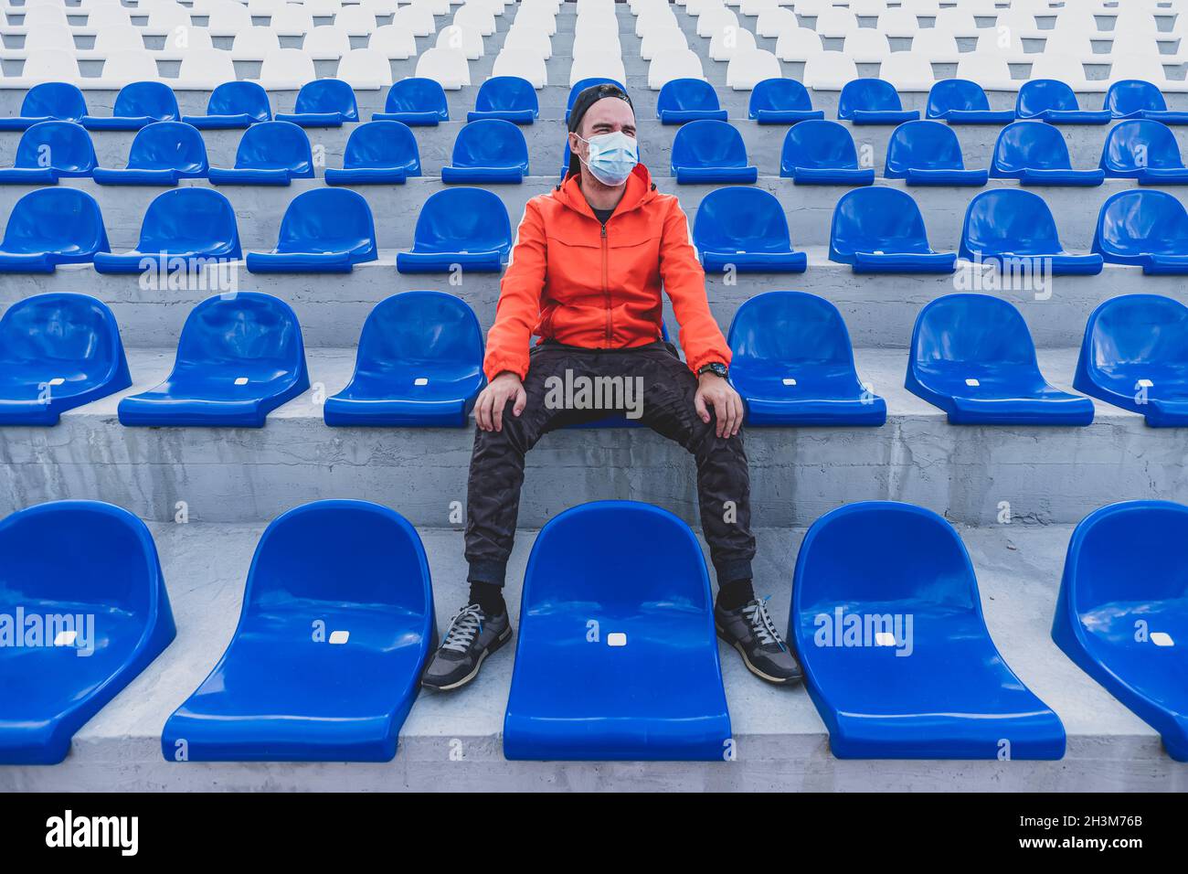 Football stands with red and blue plastic chairs. Football fan with a ...