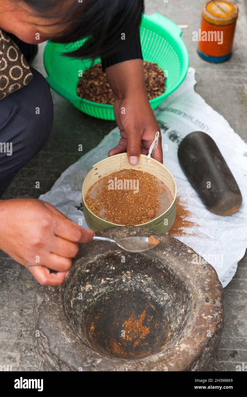 Preparing grinding powdered ground spice in a pestle and mortar before ...