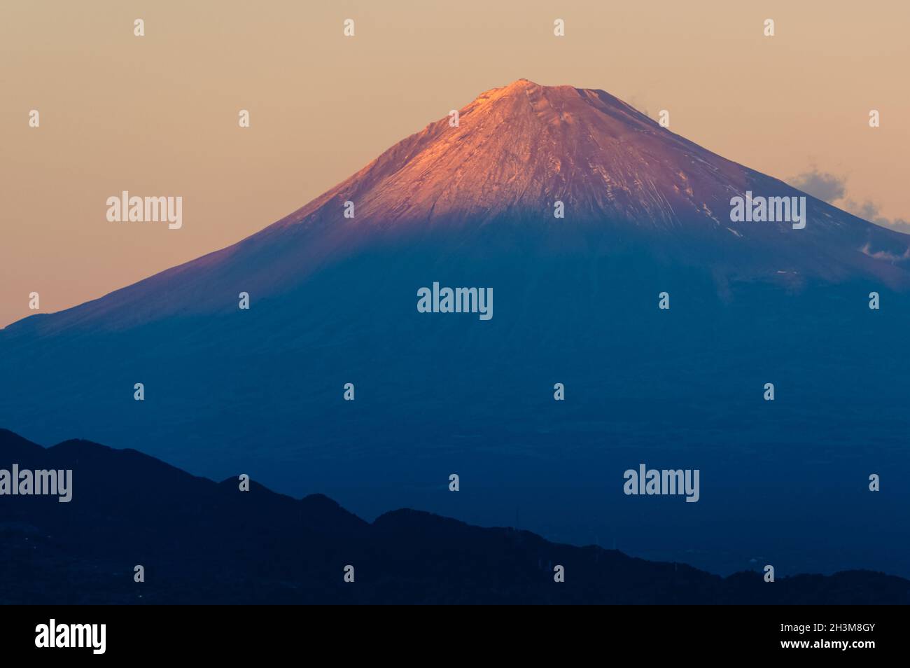 Light from the setting sun shining on the upper portion of Mt. Fuji as ...