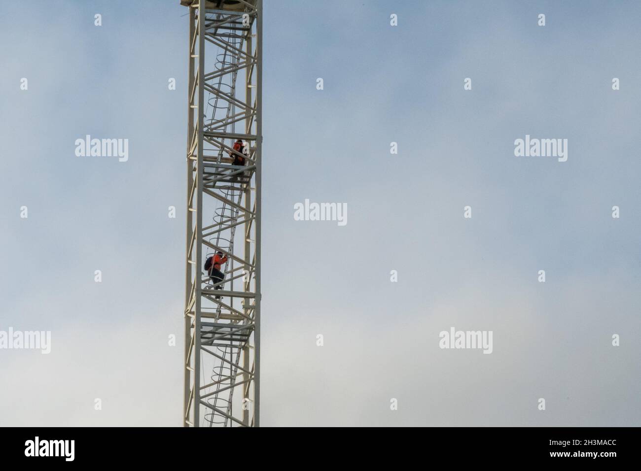 Two tower crane operators climb down the ladders high in the sky at the ...