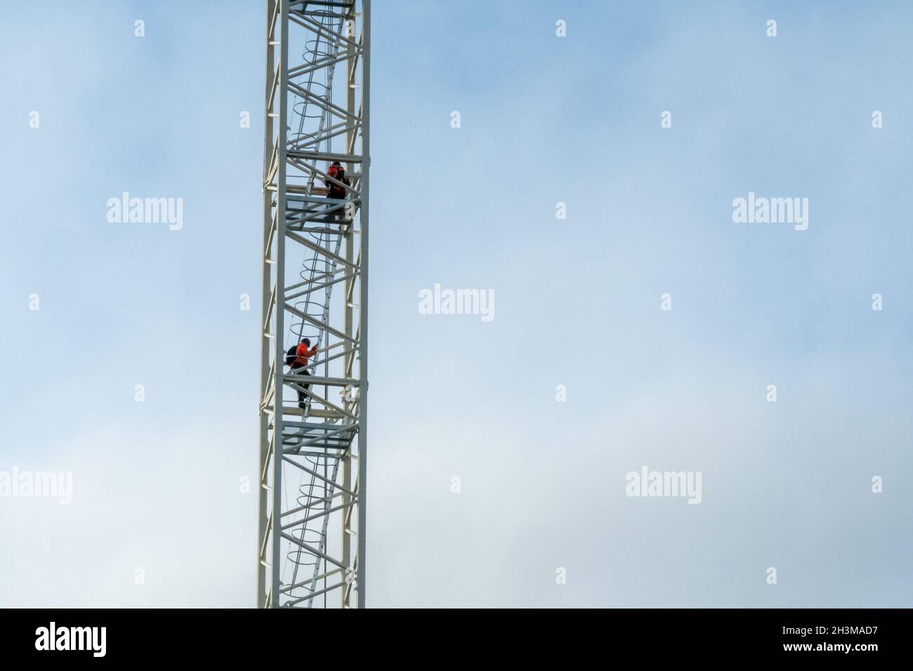 Two tower crane operators climb down the ladders high in the sky at the ...