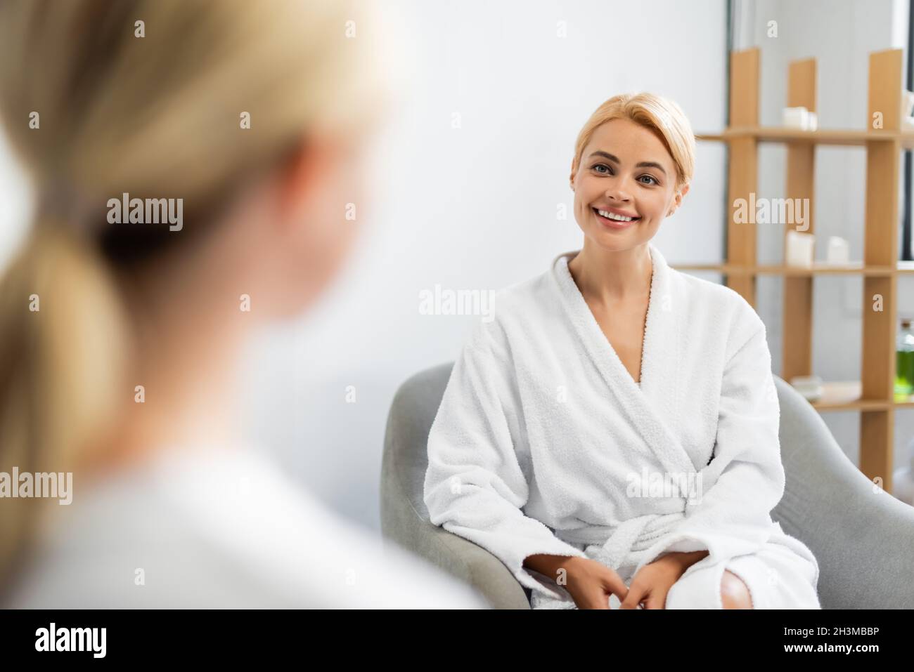 happy client in bathrobe looking at blurred spa specialist Stock Photo ...