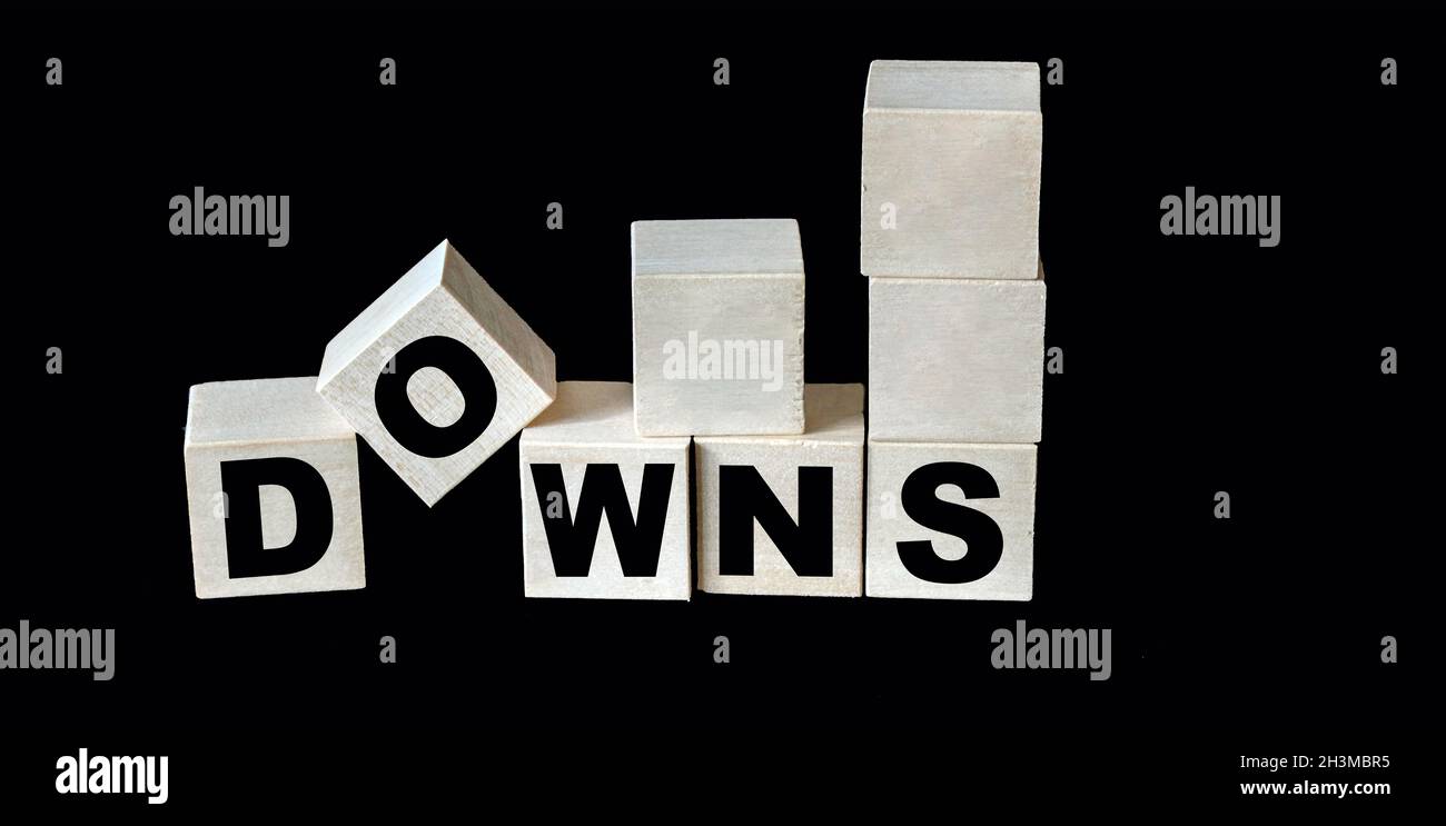 Down text and down arrows are written on wooden blocks and black glass ...