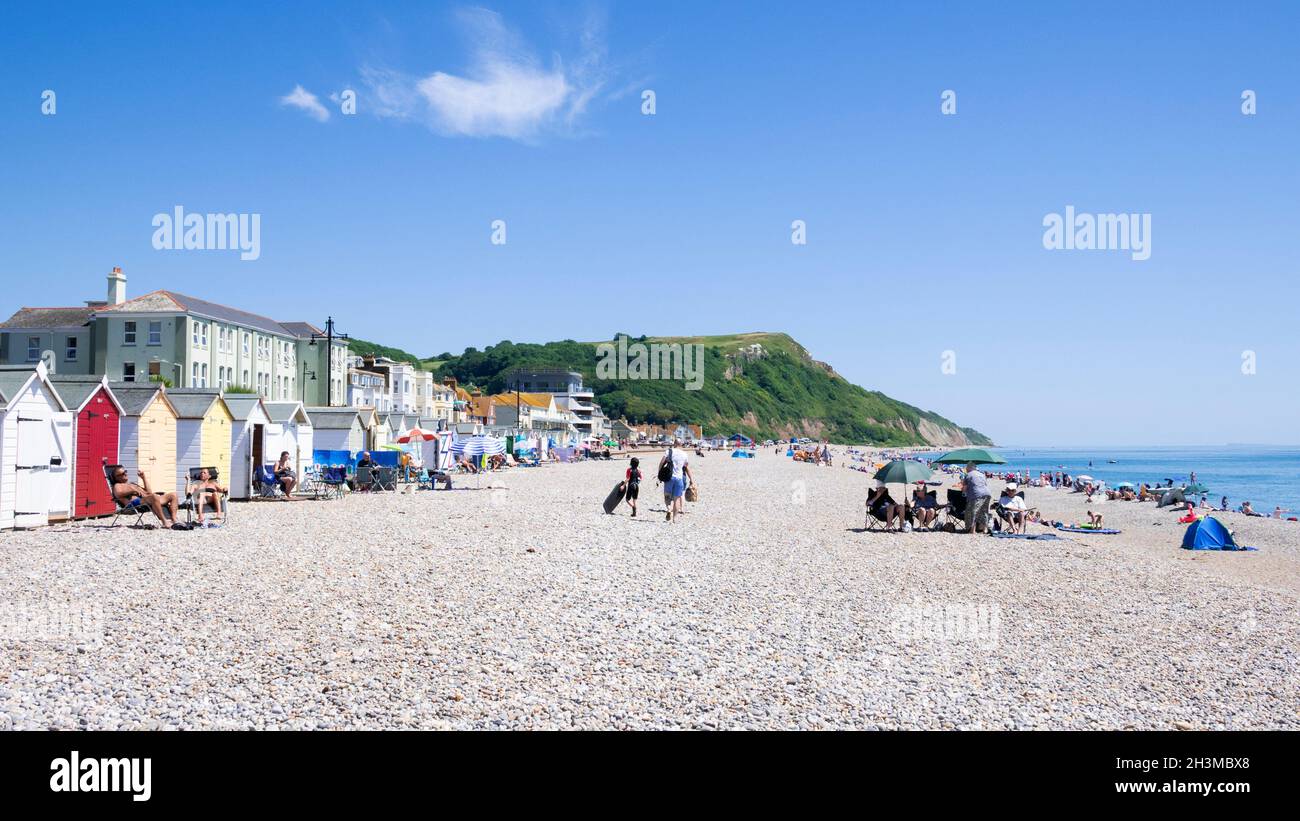 Seaton Devon Lots of people by the beach huts on the pebble beach at ...