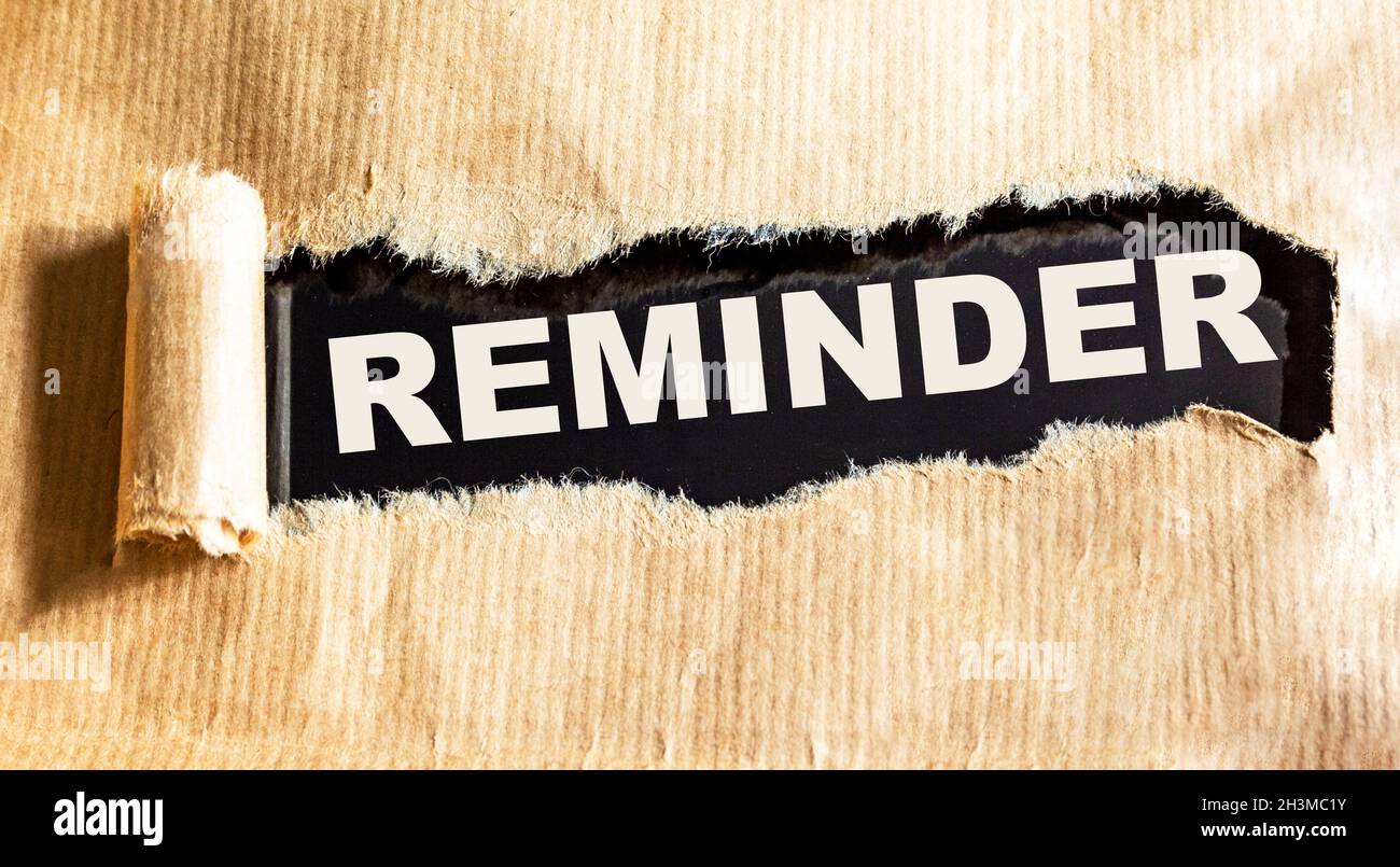 Reminder, text written on torn brown paper and black background Stock ...