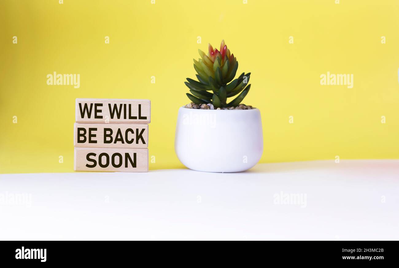 WE WILL BE BACK SOON text on wooden blocks and white and yellow ...