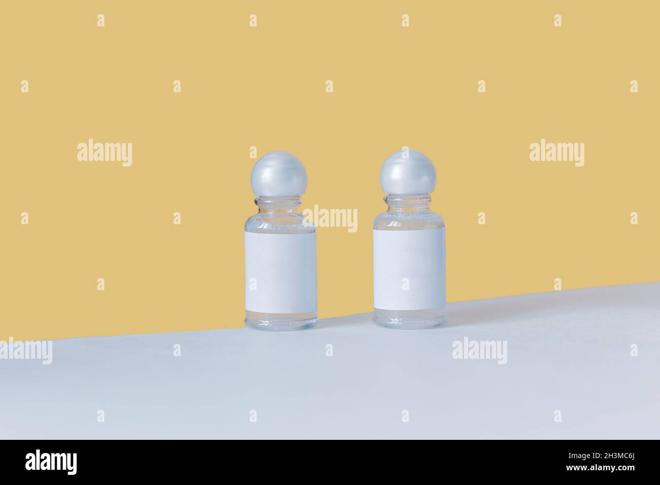 Two small bottles for shampoo or balm on a white and yellow background ...