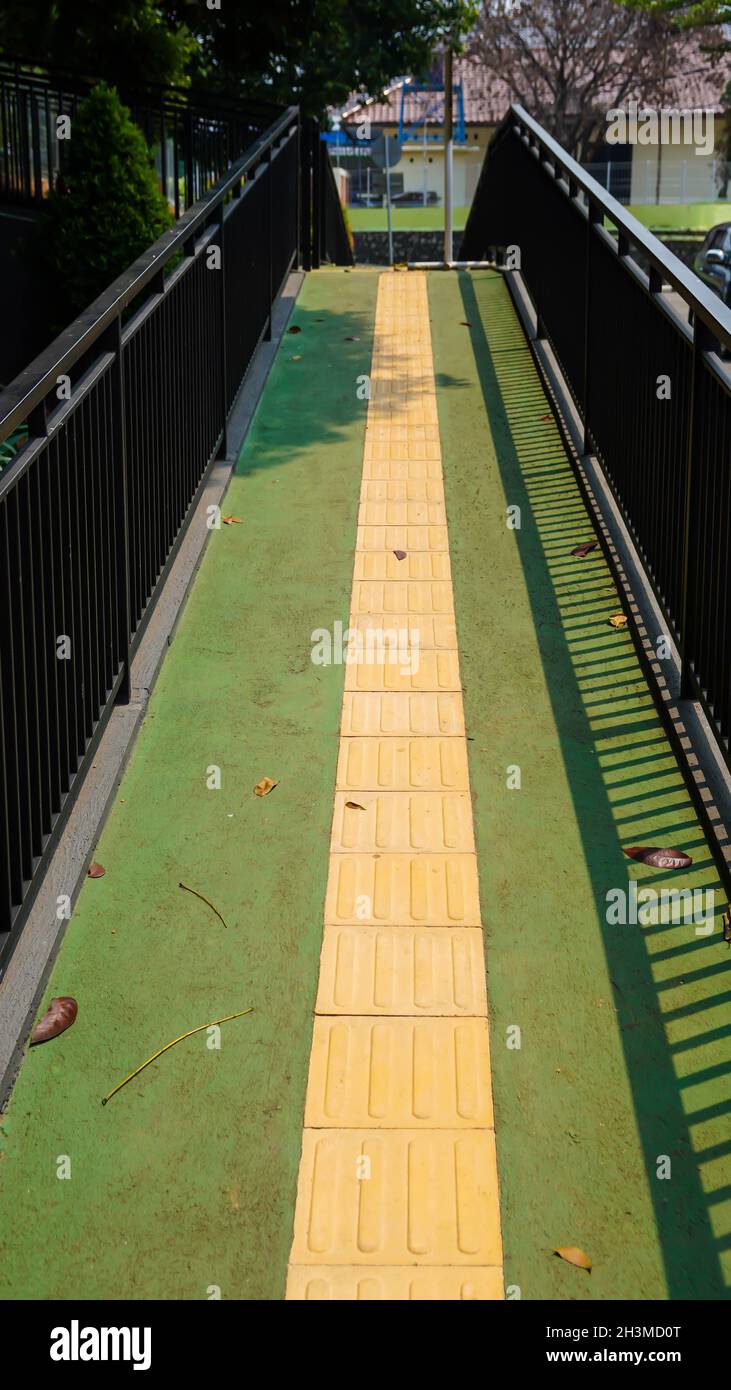 Pedestrian walking on tactile paving on footpath in selective focus ...