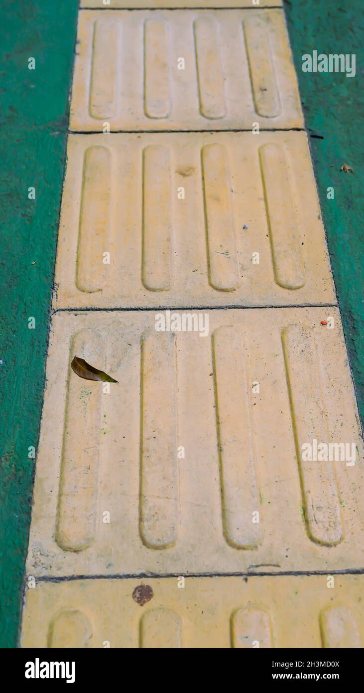 Pedestrian walking on tactile paving on footpath in selective focus ...