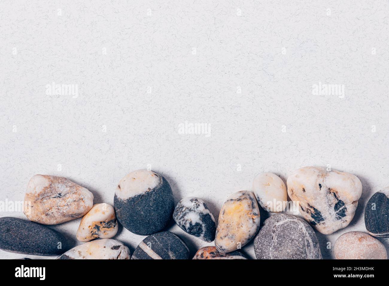 Flat lay row natural pebble stones on gray background with copy space ...