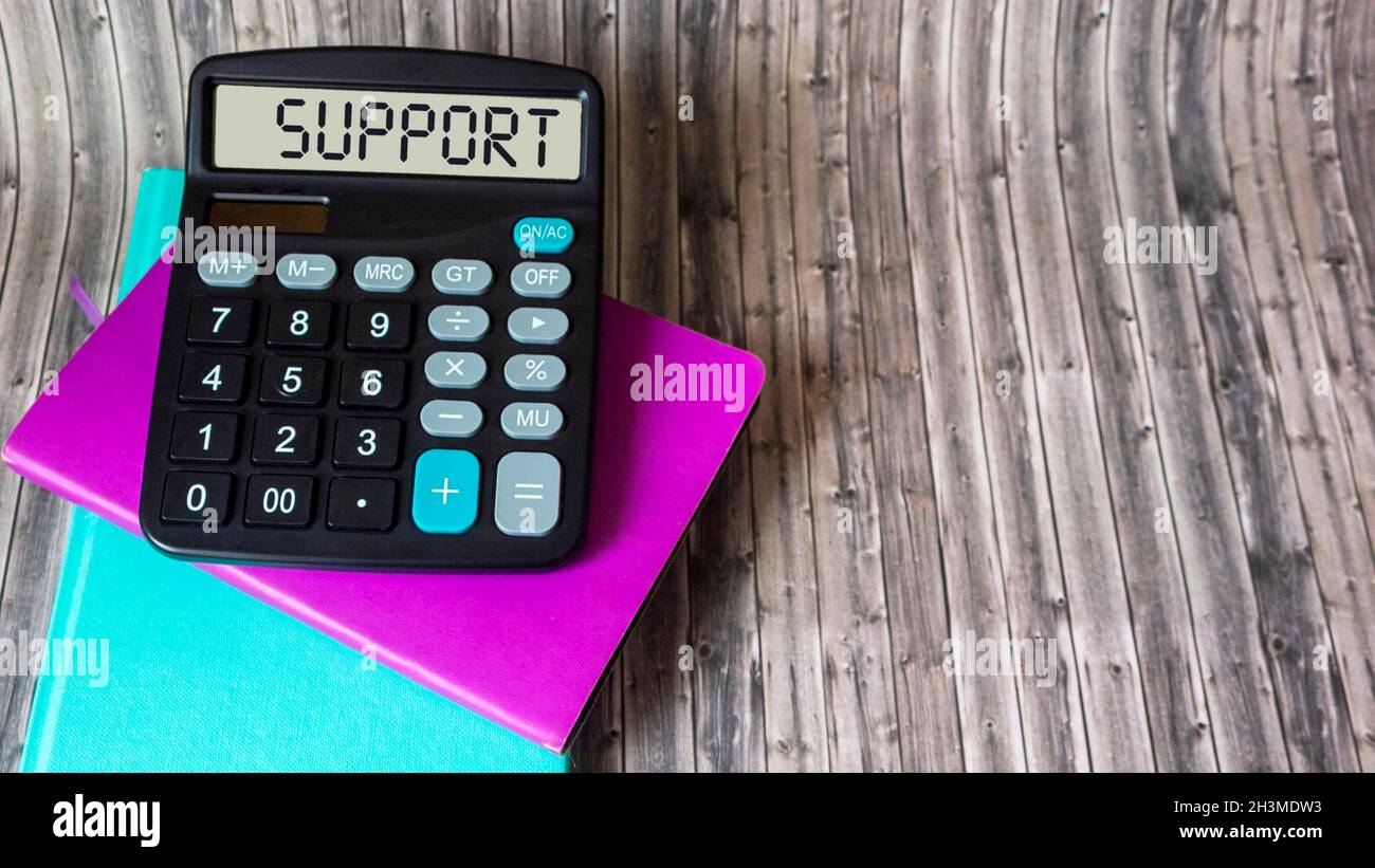 Support, text written on a calculator next to colored notepads on a ...