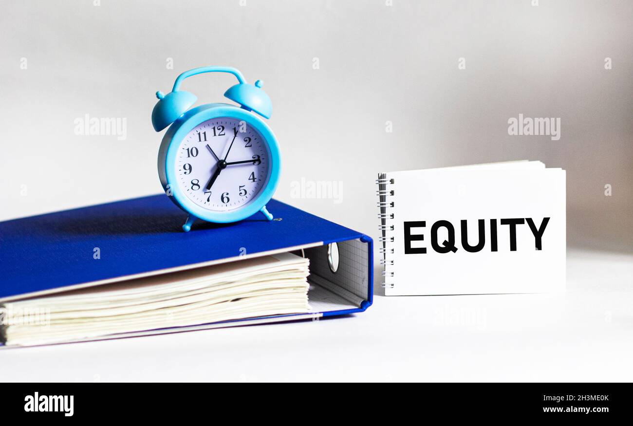 The word EQUITY is written on a notepad. Document folder and alarm ...