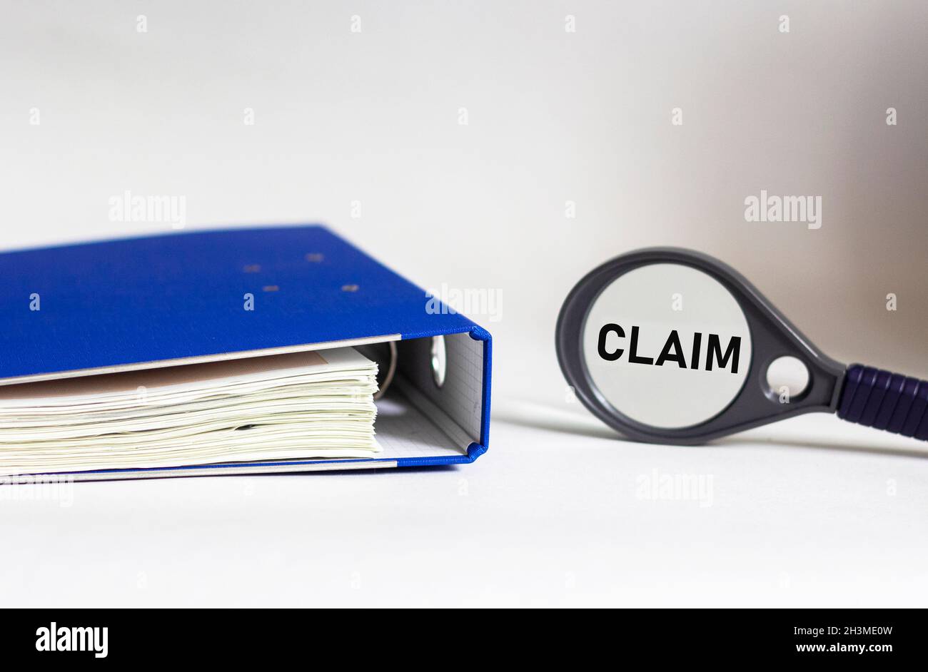 The text CLAIM written on a magnifying glass, next to a folder with ...