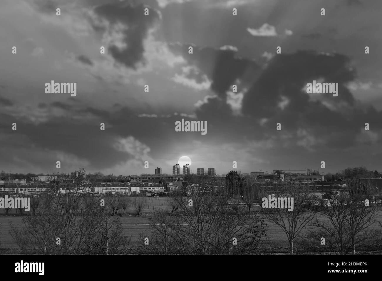 View of a city and the sun lights in the sky with clouds in grayscale ...