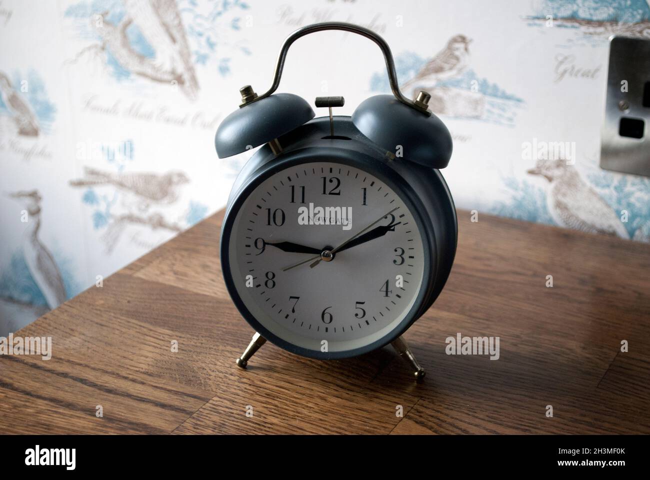 Old fashioned wind up alarm clock on side table in bedroom of pub and ...