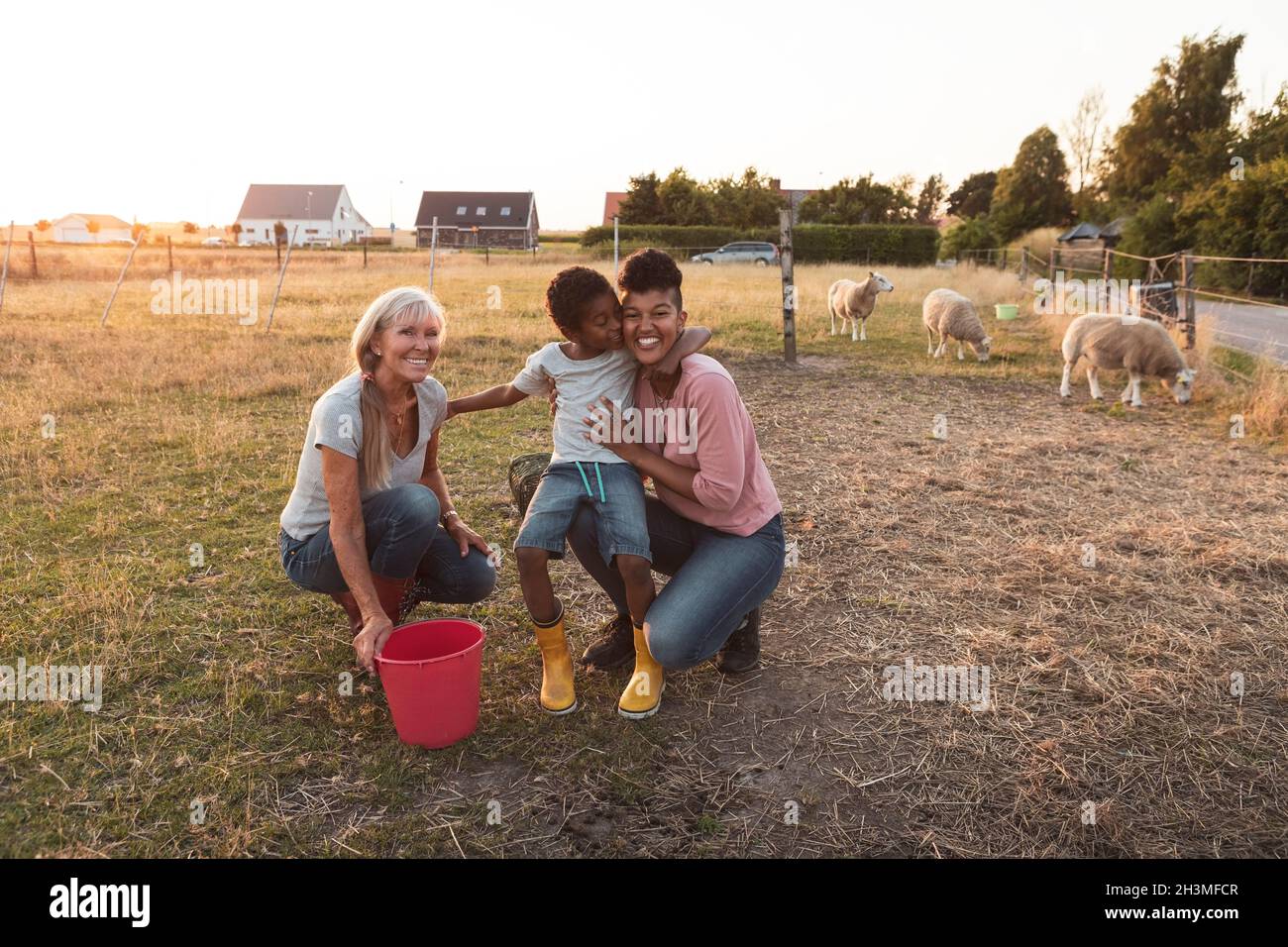 Happy multi-generational family with bucket on field at farm Stock ...