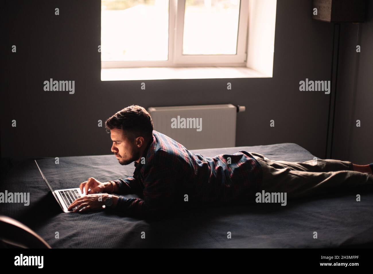 Man using laptop computer lying on bed at home Stock Photo - Alamy