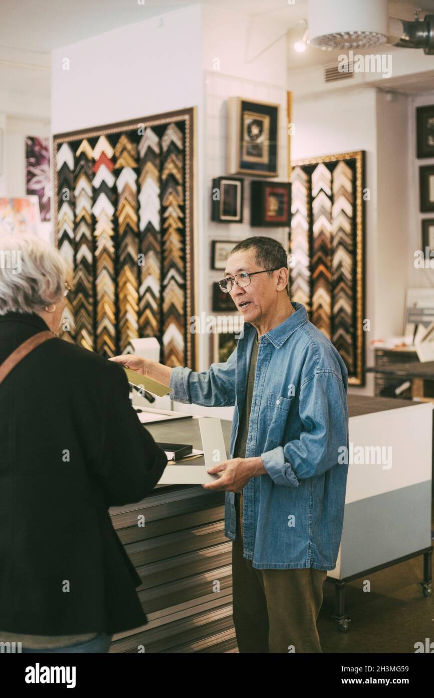 Female customer buying frame from male owner at retail shop Stock Photo ...