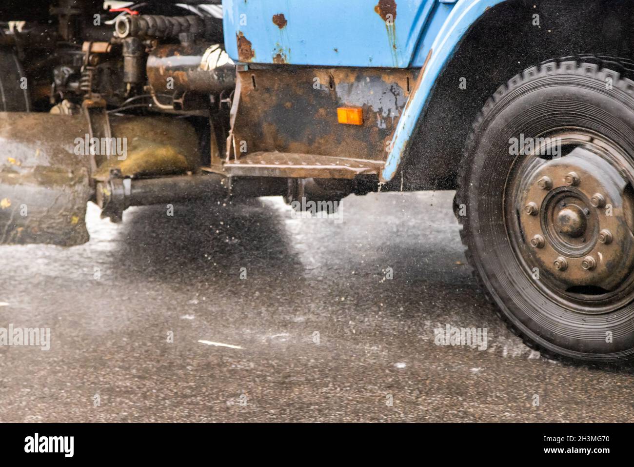 old utility truck moving on asphalt road under rainy day - close-up ...