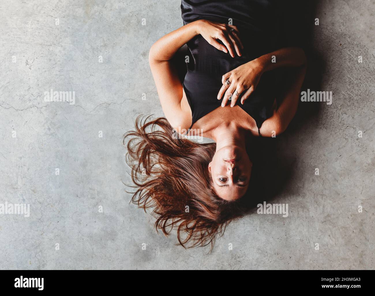 Overhead view of beautiful brunette woman laying on concrete floor ...