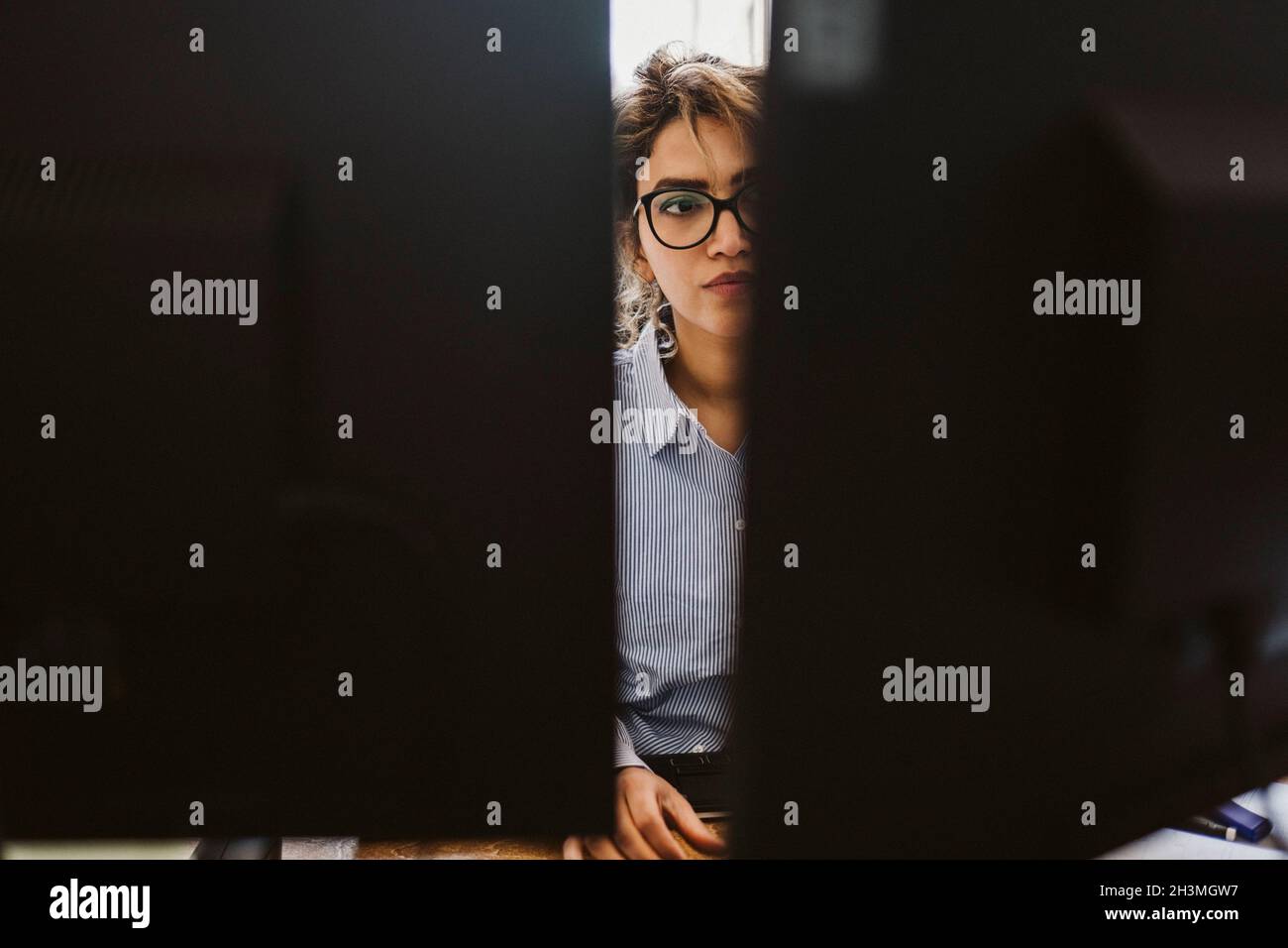 Female entrepreneur working seen through computer monitor in office ...