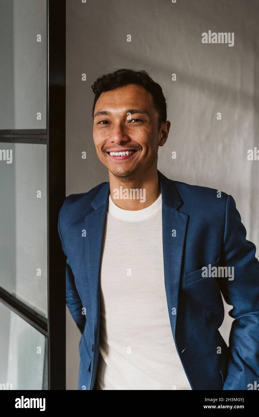 Smiling male entrepreneur leaning on doorway Stock Photo - Alamy