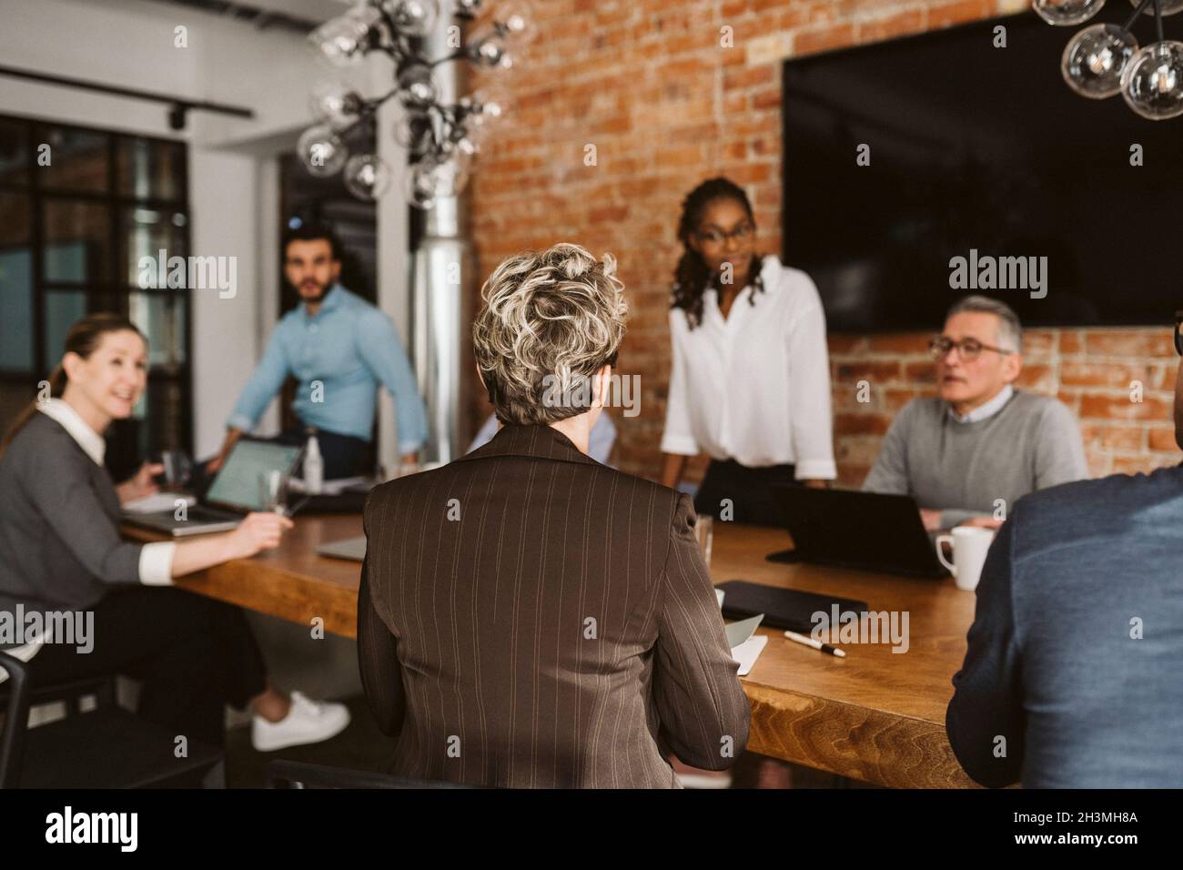 Mature businesswoman sitting at conference table discussing plan with ...