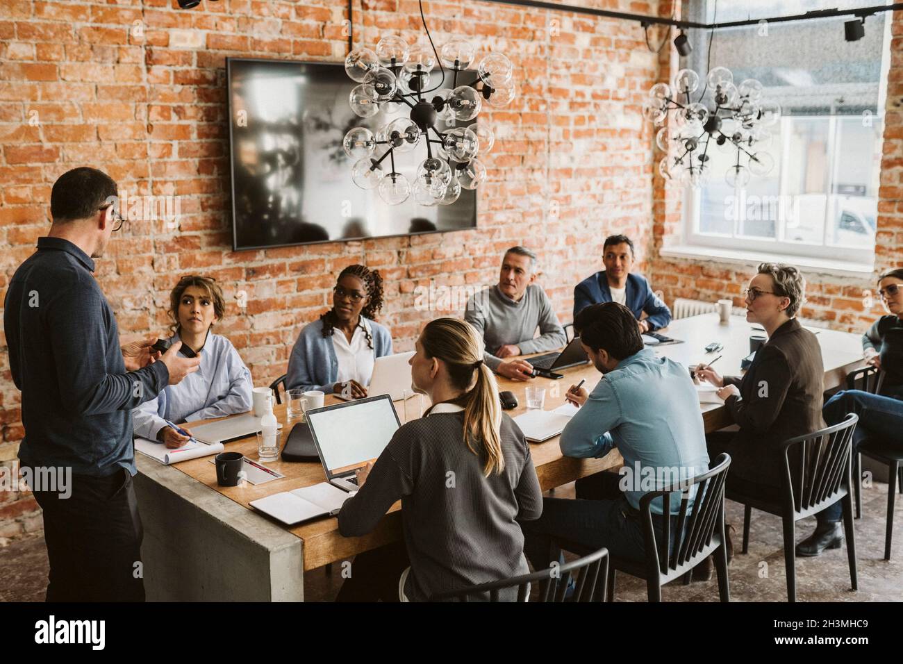 Male and female colleagues looking at business professional explaining ...