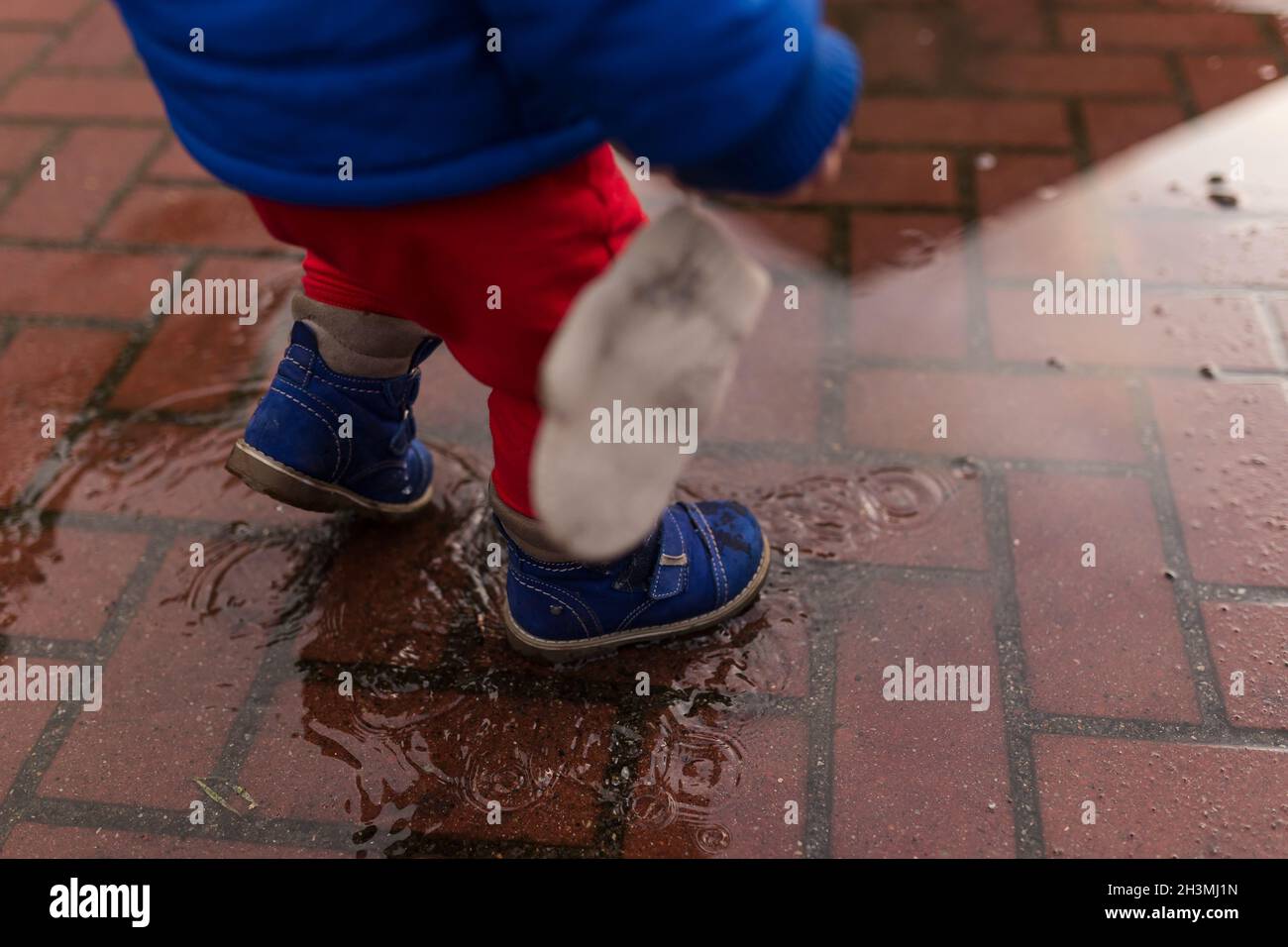 Low section of baby boy walking in puddle outside Stock Photo - Alamy