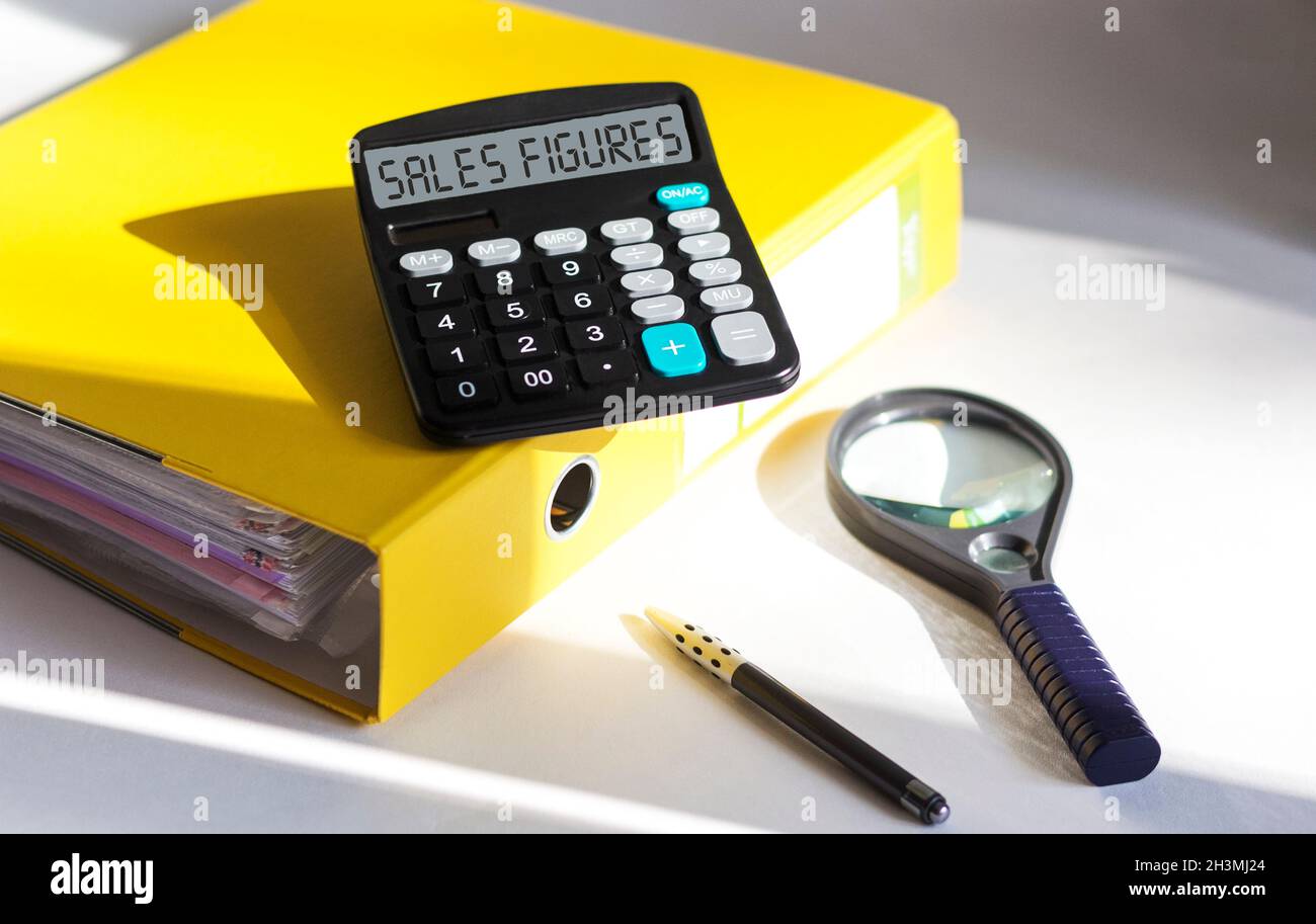Sales numbers - text on card next to document folder, magnifier ...