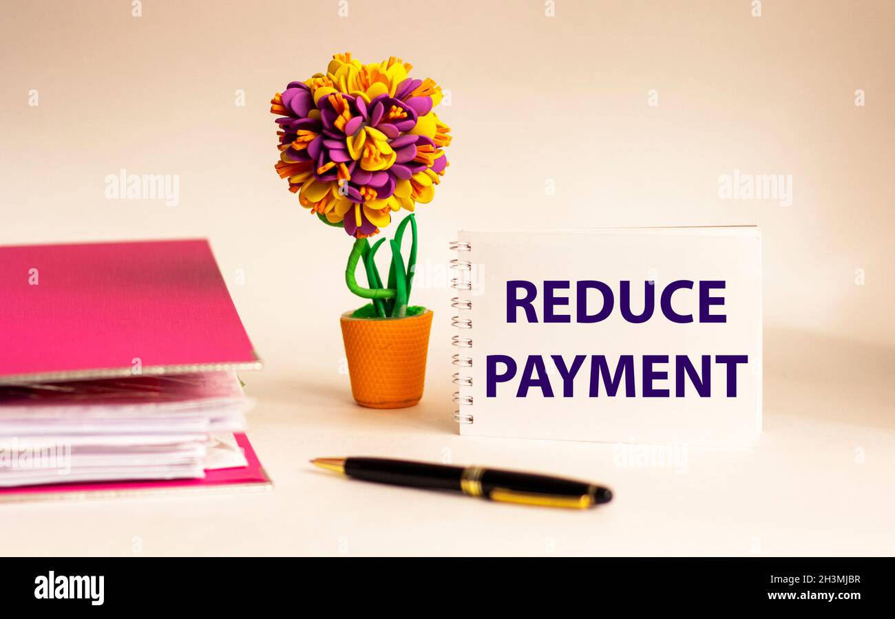 REDUCE PAYMENT text on notepad in front of document folder, pen and ...