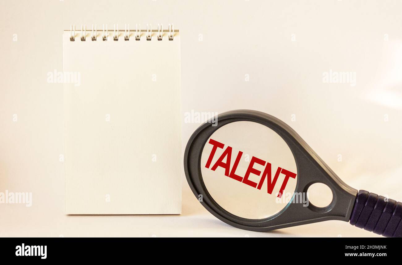 The word Talent is written on a magnifying glass. Near a notepad for ...