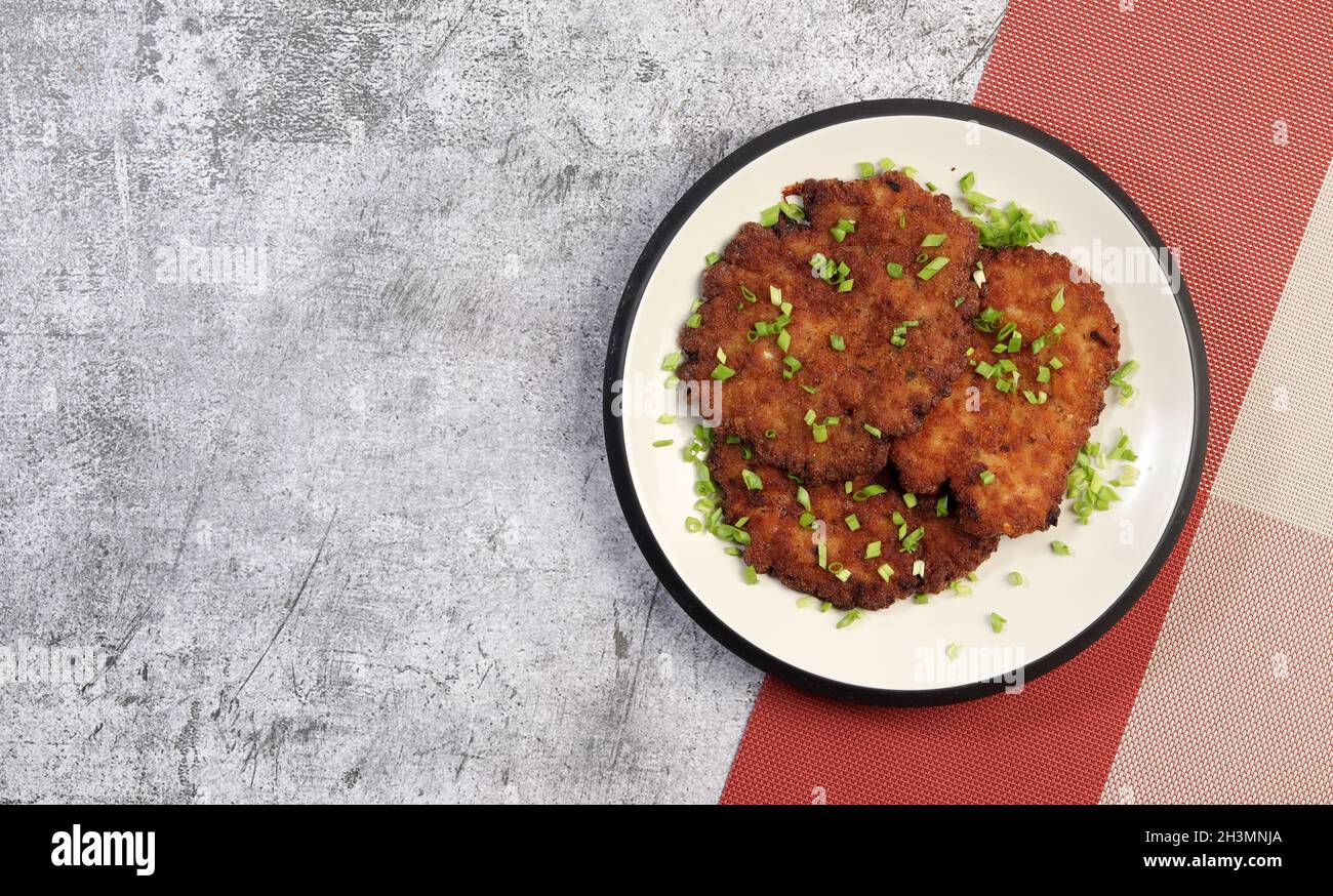 Traditional Fried Wiener Schnitzel on a round plate on a dark gray ...