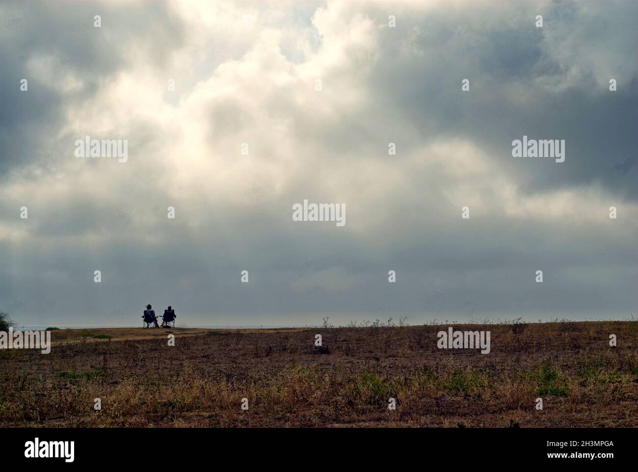 People sitting on a bench in a wide open space Stock Photo - Alamy
