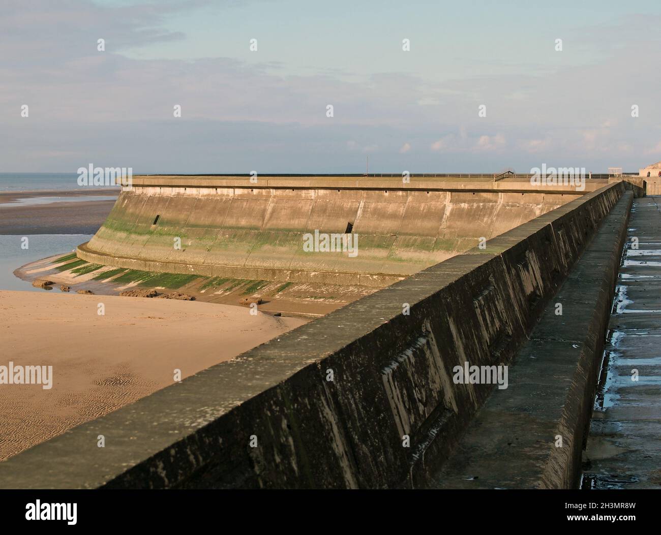 The seawall in blackpool with the beach at low tide in sunlight with ...