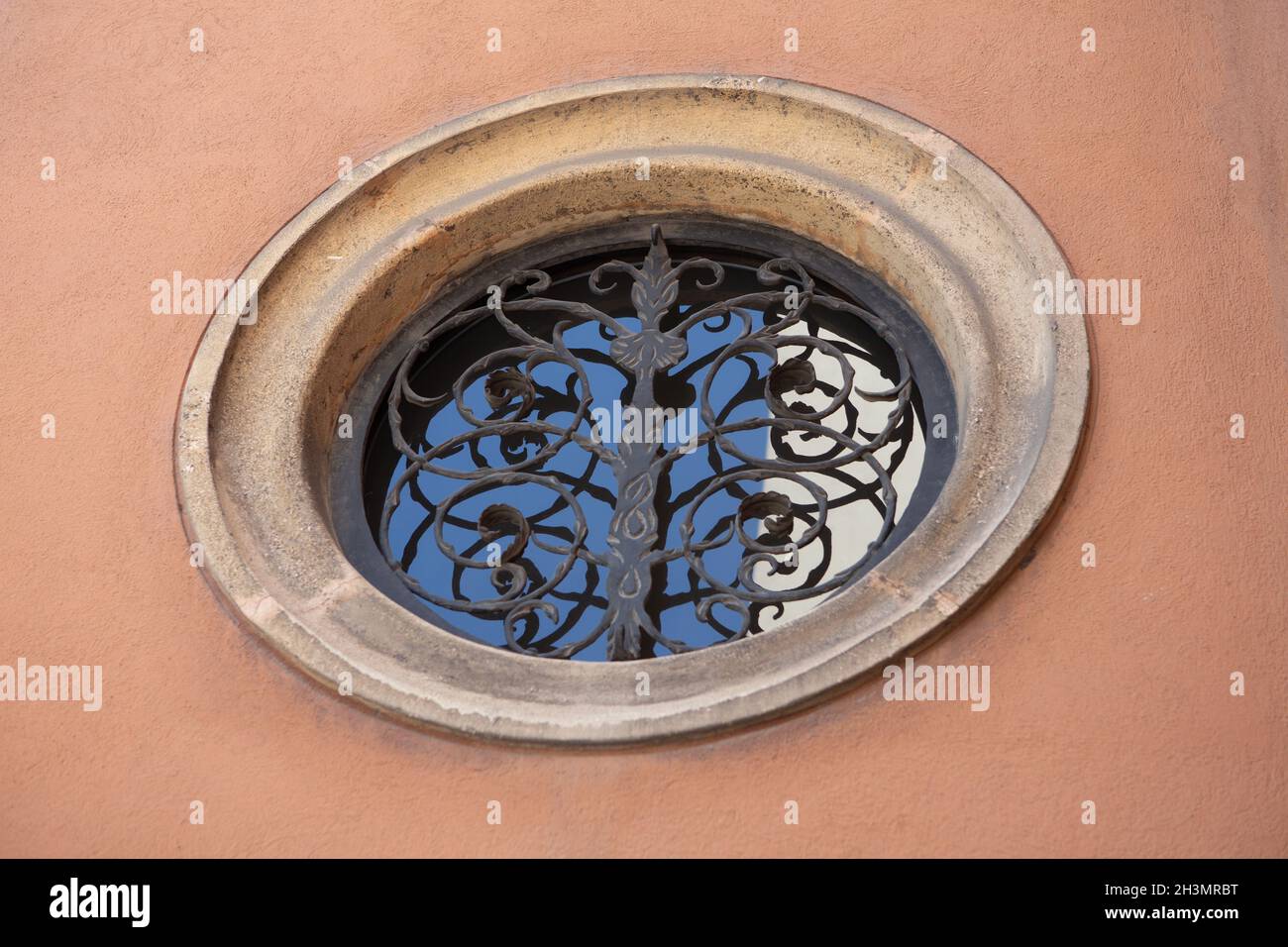 Antique round window with ornate metal bars on the plastered wall of ...